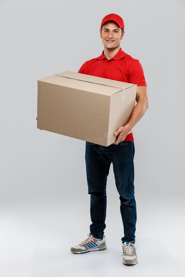 Young Delivery Man in Hat Smiling while Posing with Cardboard Box Stock ...
