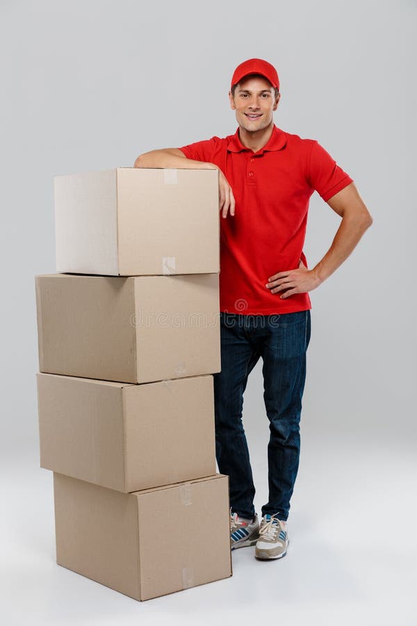 Young Delivery Man in Hat Smiling while Posing with Cardboard Boxes ...