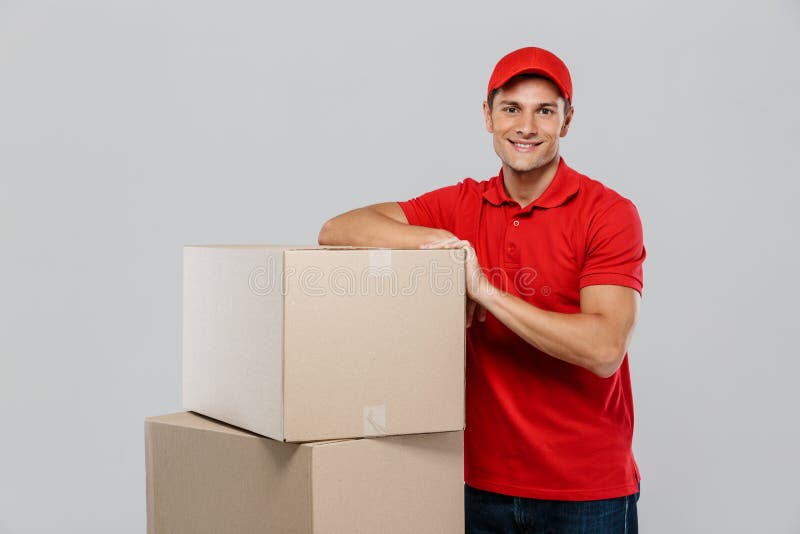 Young Delivery Man in Hat Smiling while Posing with Cardboard Boxes ...