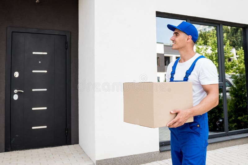 Young Delivery Man Hold a Cardboard Box in His Hands Stock Photo ...