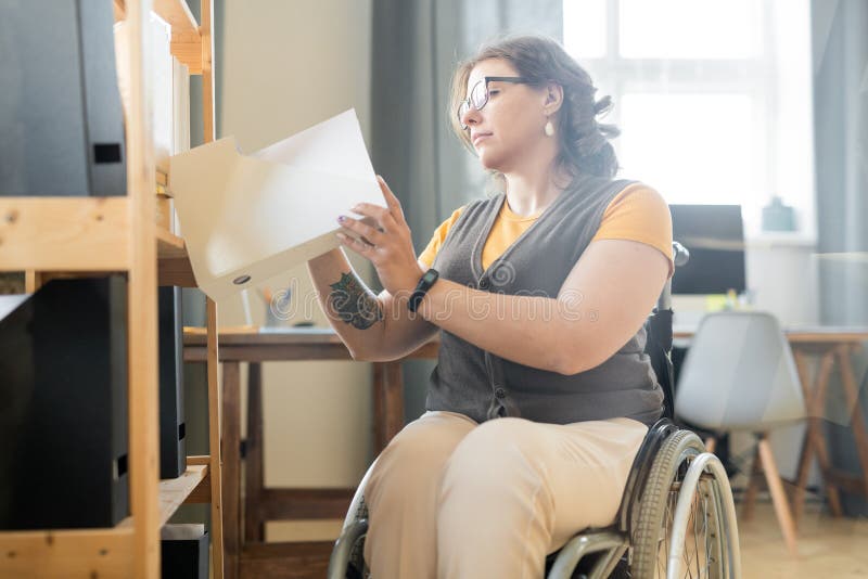 Young Disable Female Office Worker Looking through Papers in One of ...