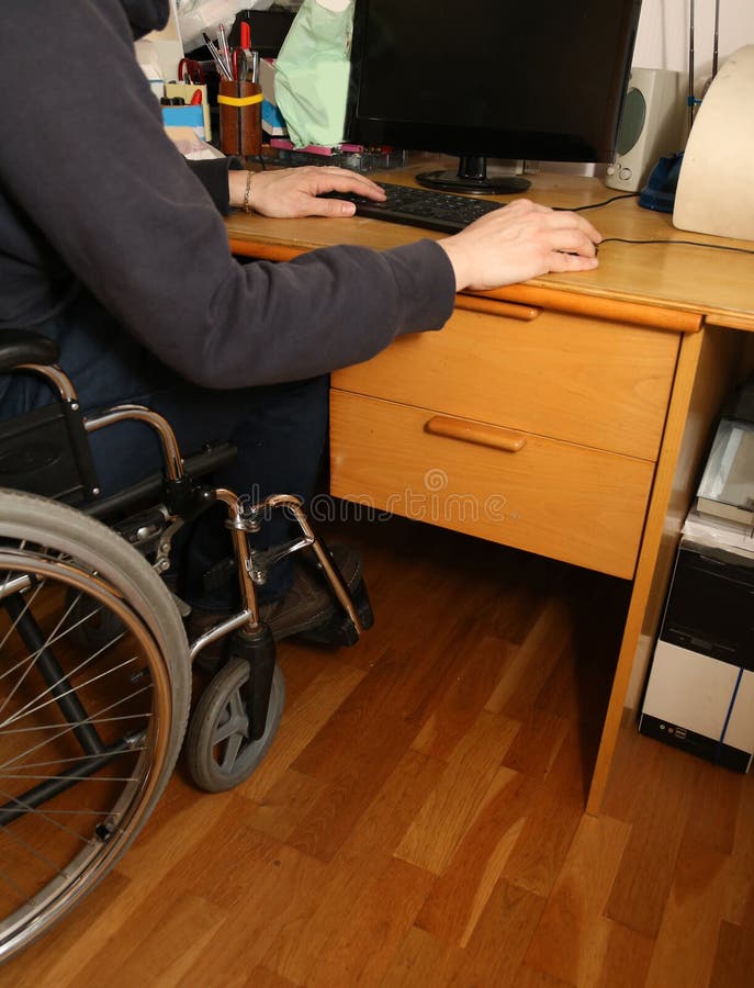 Young Disabled Man in a Wheelchair Using the Computer on the Des Stock ...