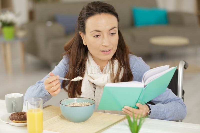 Young Disabled Woman Reading Book while Eating Breakfast Stock Image ...