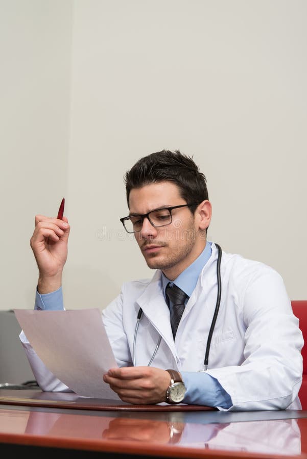Young Doctor in Office Looking at Paper Stock Image - Image of coat ...