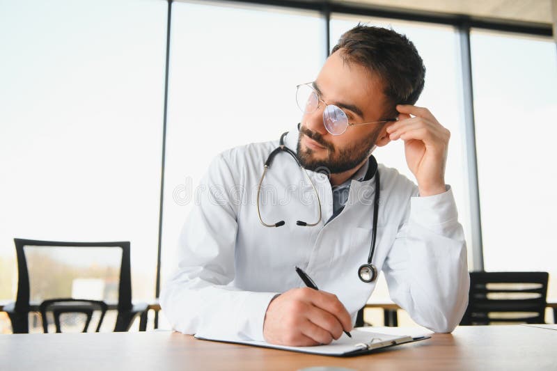 Young Doctor Sitting in His Office Behind a Desk Stock Photo - Image of ...