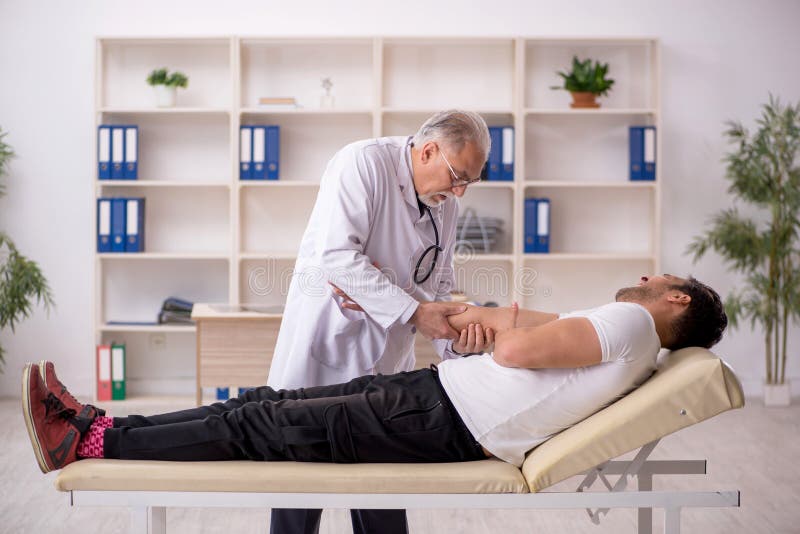 Young Male Doctor Visiting Old Doctor Chiropractor Stock Photo - Image ...