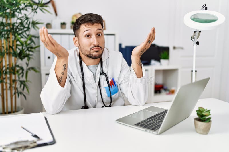 Young Doctor Working at the Clinic Using Computer Laptop Clueless and ...