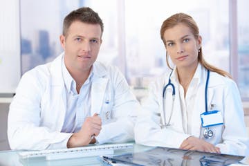 Young Doctors Sitting at Desk Consulting Stock Image - Image of clinic ...
