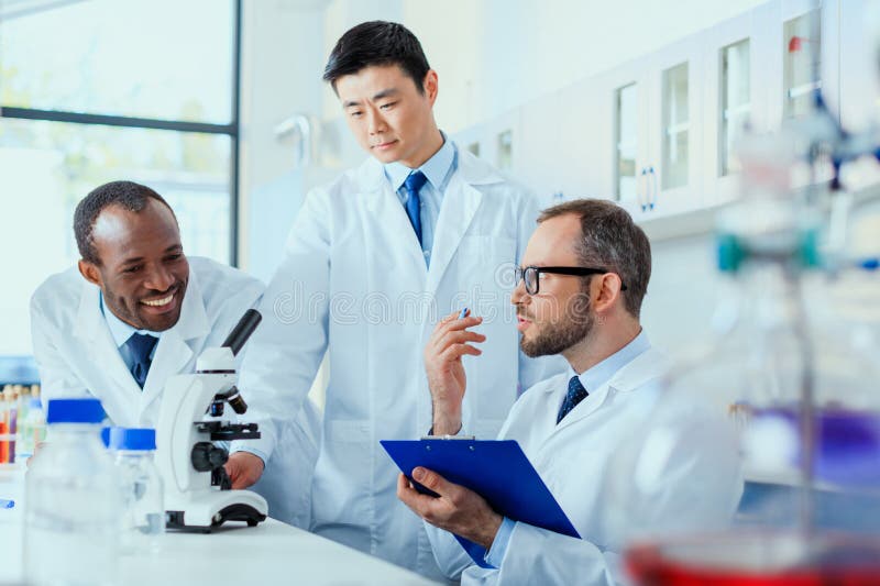 Young Lab Technicians Working with Microscope and Taking Notes on ...