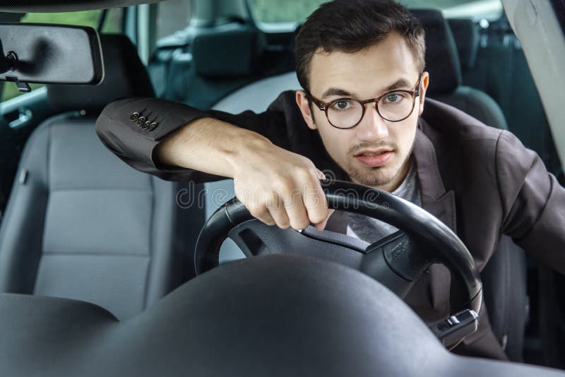 Young Driver is Looking at the Camera while Driving His Car. he Holding ...