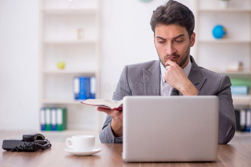 Young Male Employee Reading Book in the Office Stock Image - Image of ...