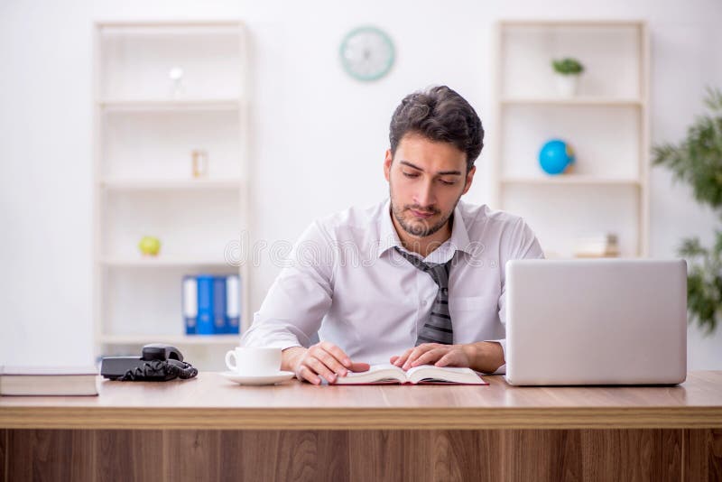 Young Male Employee Reading Book in the Office Stock Photo - Image of ...