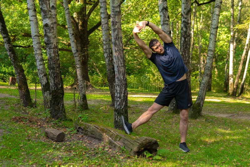 A Young Enduring Athletic Athlete is Doing Stretching in the Forest ...
