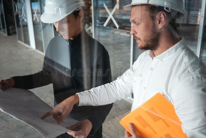 Young Engineer Discussing with Building Worker on Construction Site ...