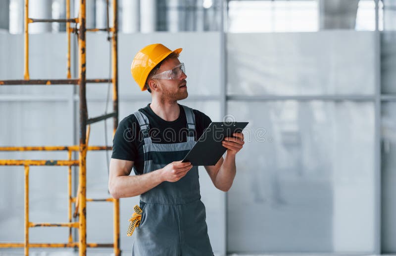 Young Engineer in Grey Uniform with Notepad Works Indoors in Modern Big ...