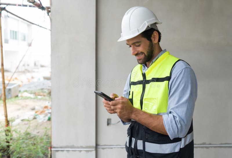 Young Engineer in Hardhat and Safety Vest Typing Text Massage on Mobile ...