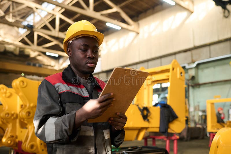 Young Engineer in Hardhat and Workwear Looking through Instruction ...