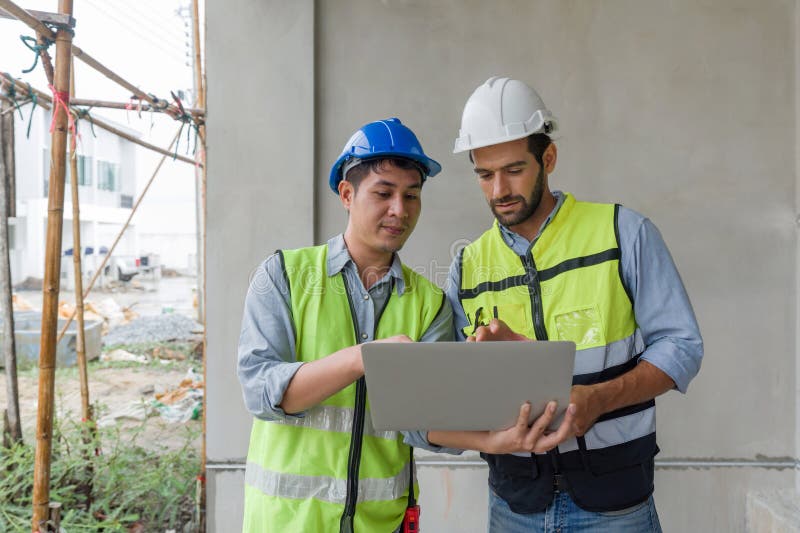 Young Engineer with Laptop Computer Explain To Foreman about a Floor ...