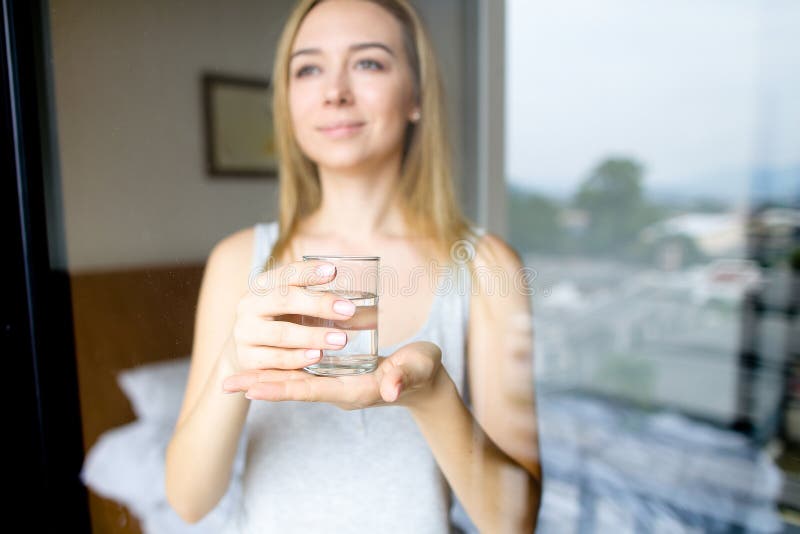 Young European Woman Drinking Glass Of Water At Hotel In Morning Stock