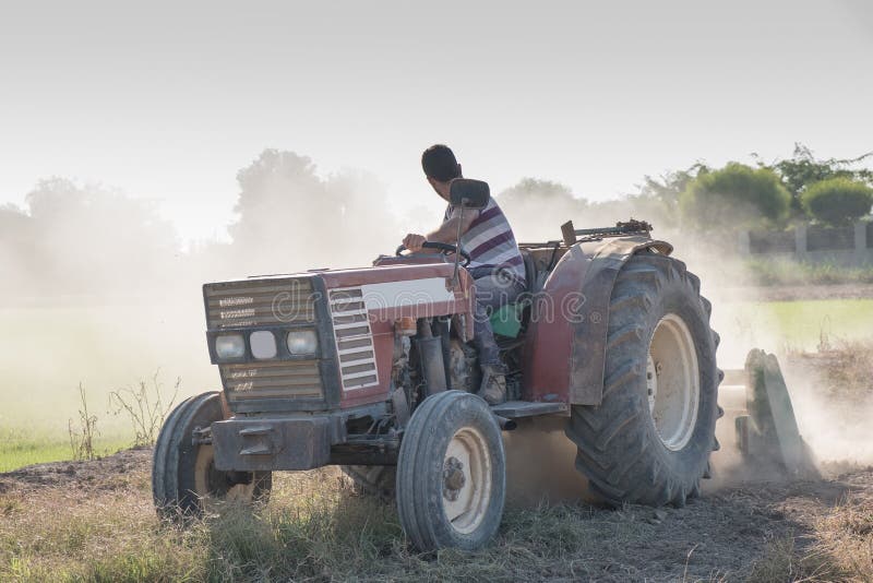 Young Farmer Enveloped in Dust while Working with a Tractor Stock Photo ...