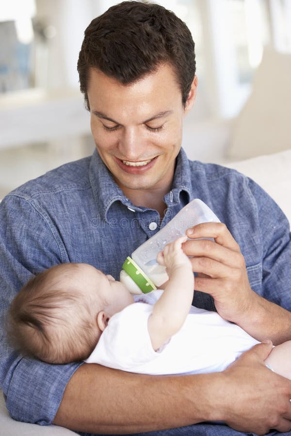 Young Father with Baby Feeding on Sofa at Home Stock Photo - Image of ...