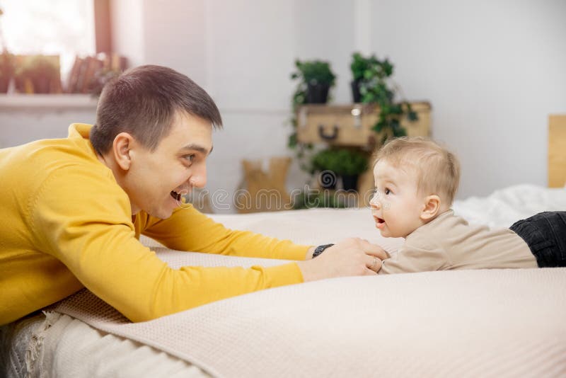 Young Father is Playing with Newborn Baby on Bed. Dad and Son Concept ...