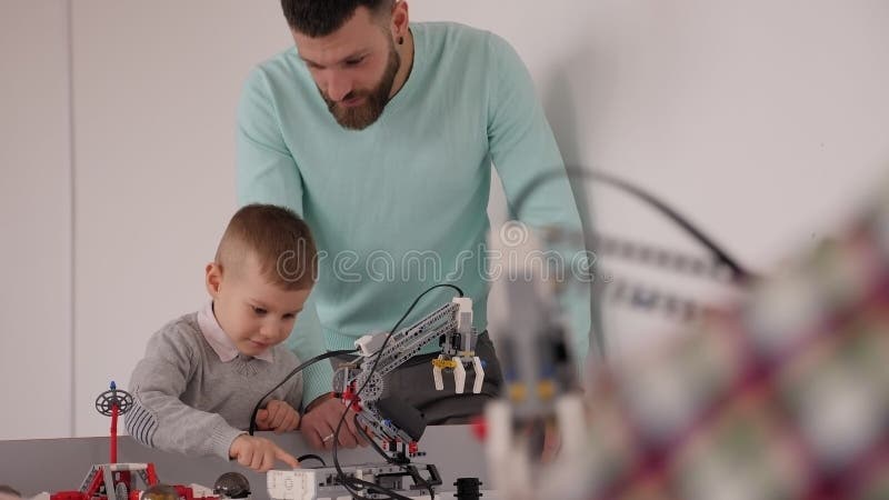 A Young Father and Son Control Robots Assembled from a Construction Kit ...