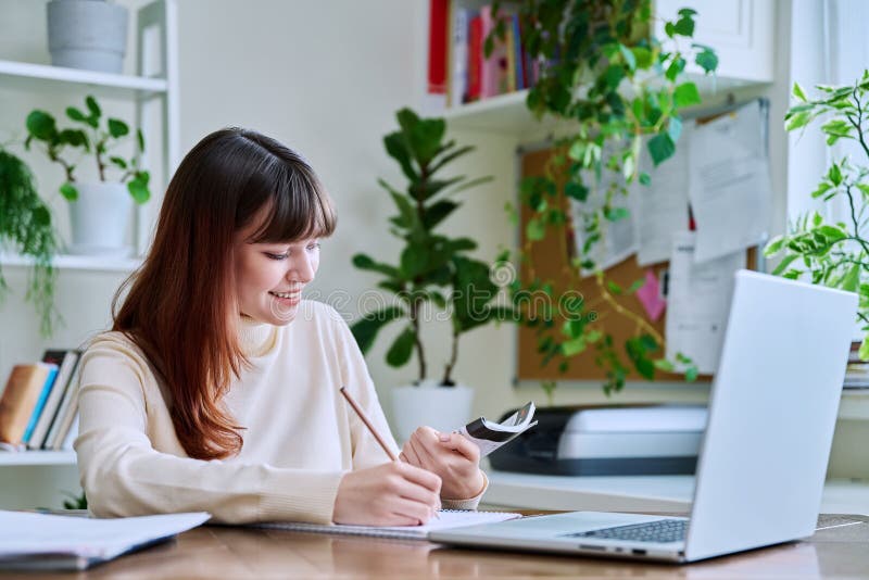 Young Female College Student Studying at Home Using Laptop, Writing in ...