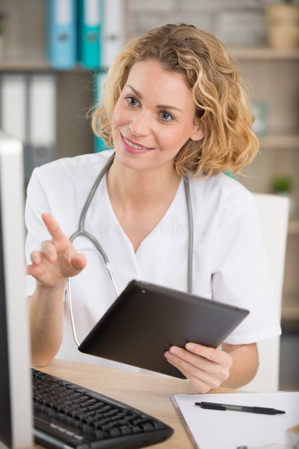 Young Female Doctor Sitting at Desk in Doctors Office Stock Photo ...