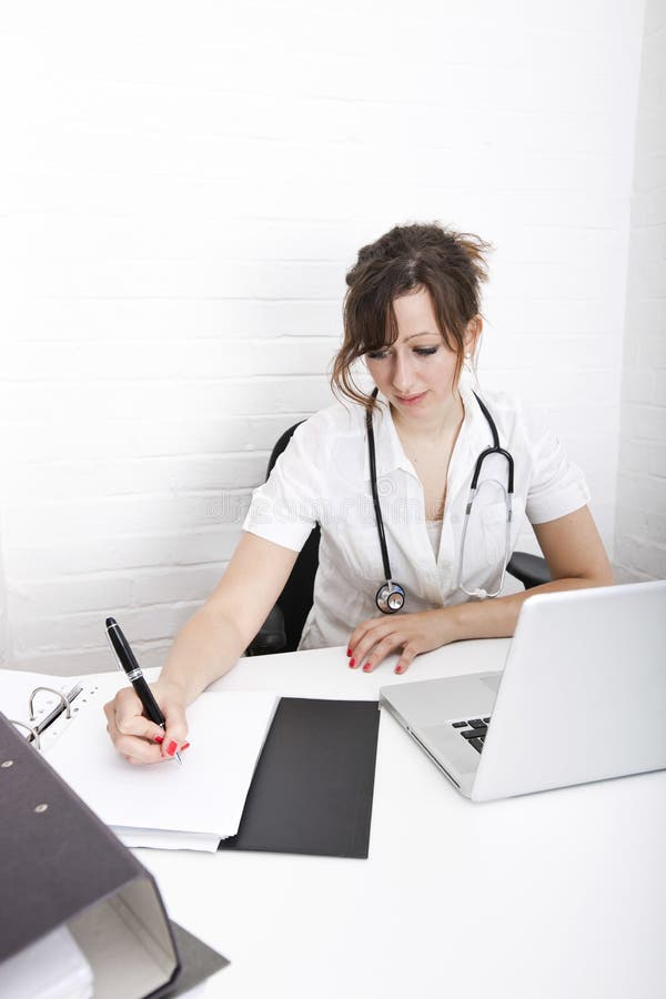 Young Female Doctor Writing Notes on Desk in Clinic Stock Image - Image ...