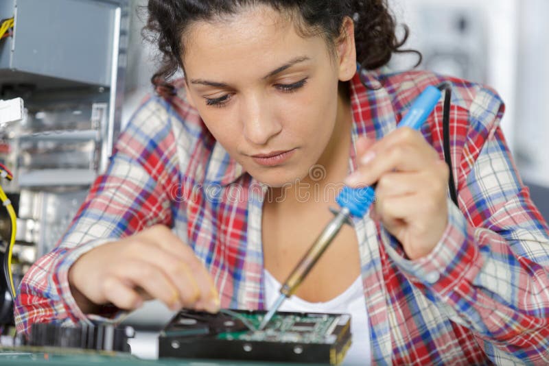 Young Female Electronic Engineer Soldering Computer Motherboard in ...