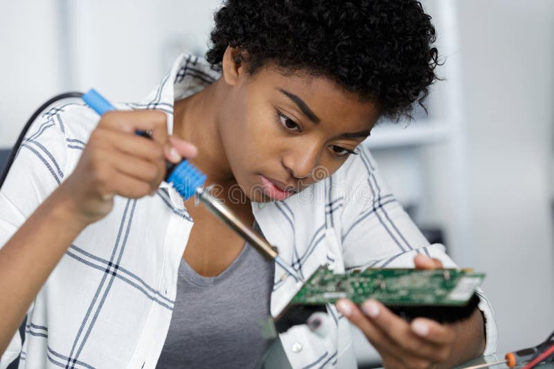 Young Female Electronic Engineer Soldering Computer Motherboard in ...