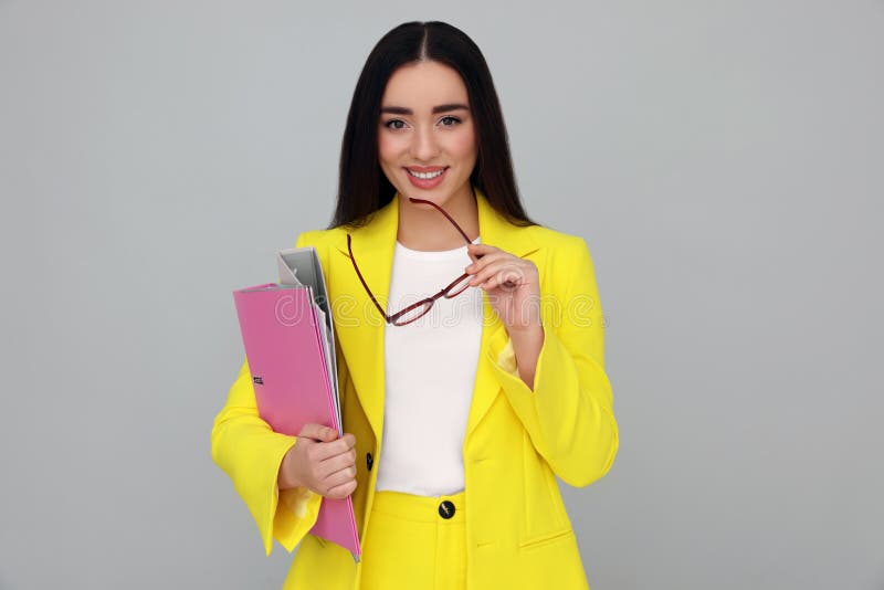 Young Female Intern with Eyeglasses and Folders on Grey Background ...