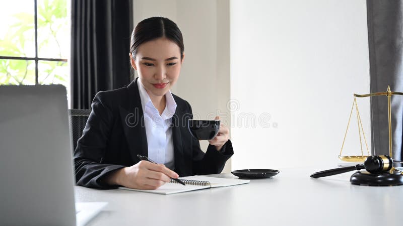 Young Female Lawyer Reading Judiciary Law Document and Using Laptop at ...