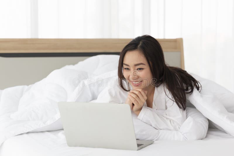 Young Female Lying On Bed Using Notebook Computer Happy Female Using