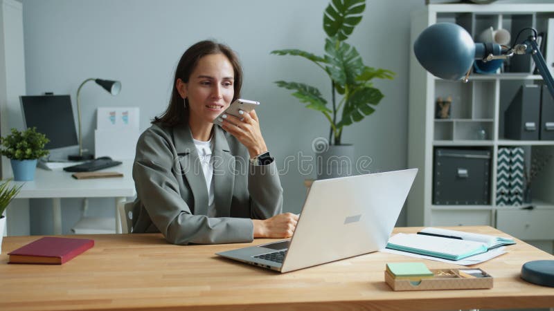Young Female Office Worker is Recording Audio Message Using Smartphone ...