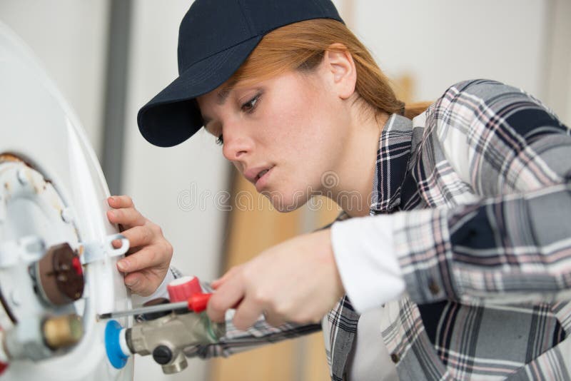 Young Female Plumber Working on Water Heater Stock Photo - Image of ...