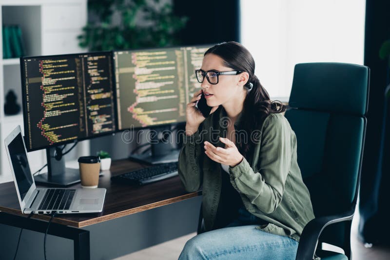 Young Female Programmer Working on Coding Tasks at Her Desk in a Modern Workspace with Multiple ...