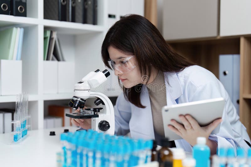 Young Female Scientist Using Microscope and Tablet in Modern Laboratory ...