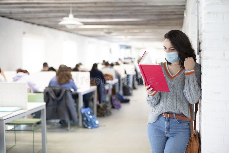Young Female Student with Face Mask Reading a Book Inside a Classroom ...