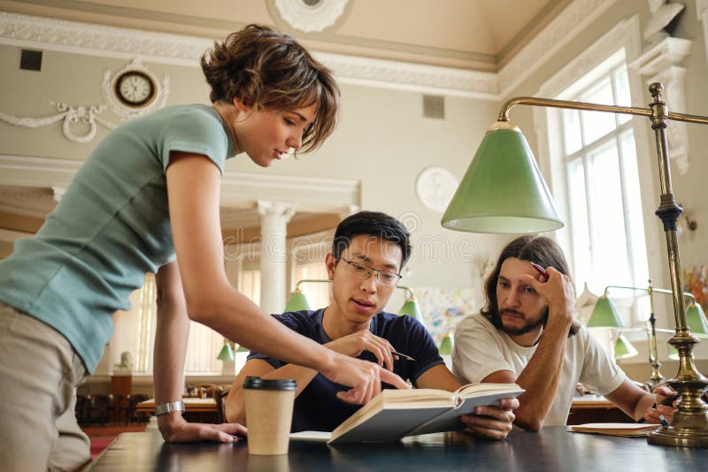 Young Female Tutor Helping Thoughtful Multinational Students with Study ...