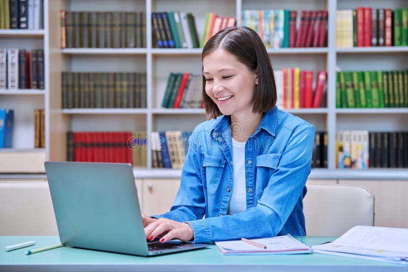 Young Female University Student Studying Inside Library, Typing on ...