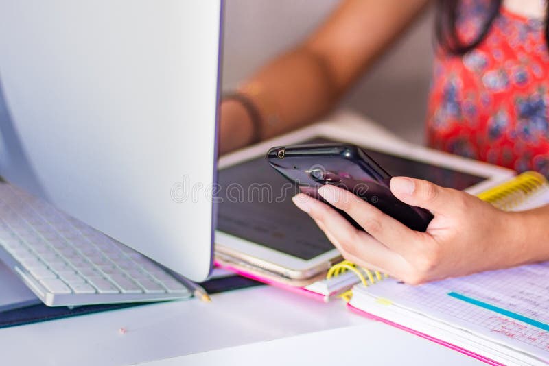 Young Female Using a Cellphone while Studying with a Tablet and ...