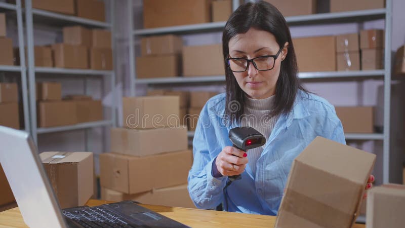 A Young Female Warehouse Worker Uses a Barcode Scanner in Her Work ...
