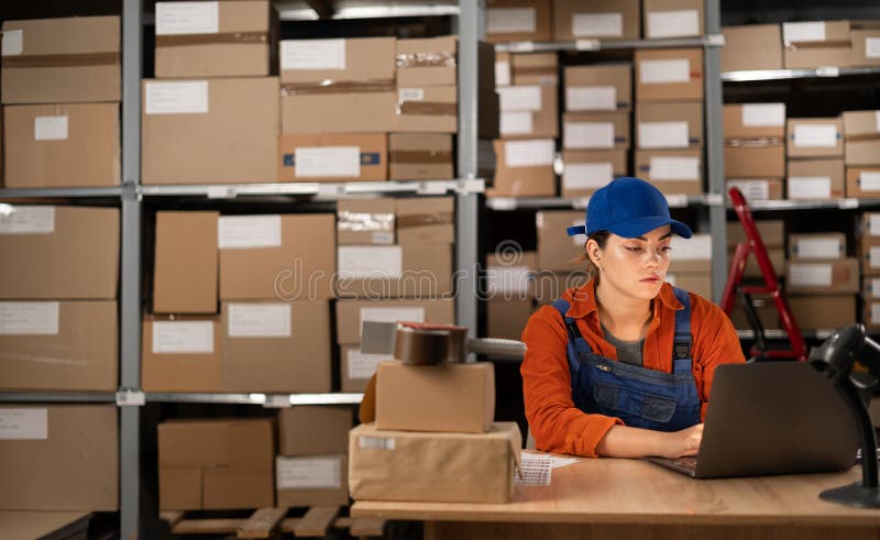 Young Female Worker Working with Laptop Computer in Storage Warehouse ...