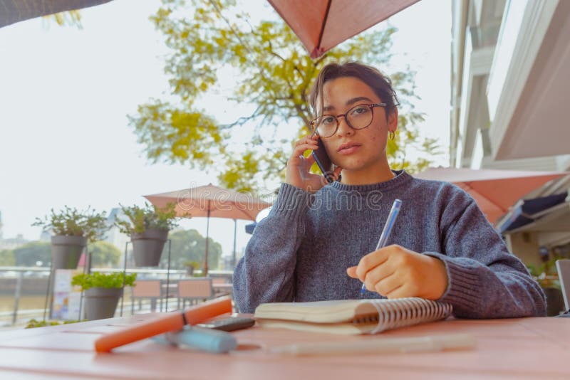 Young Female is Writing in a Notebook while Seated at a Table in a ...
