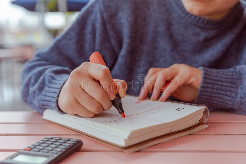 Young Female is Writing in a Notebook while Seated at a Table in a ...