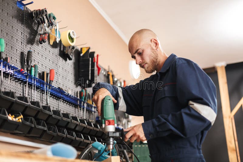 Young Foreman in Work Clothes Using Electric Drill with Stand of Stock ...