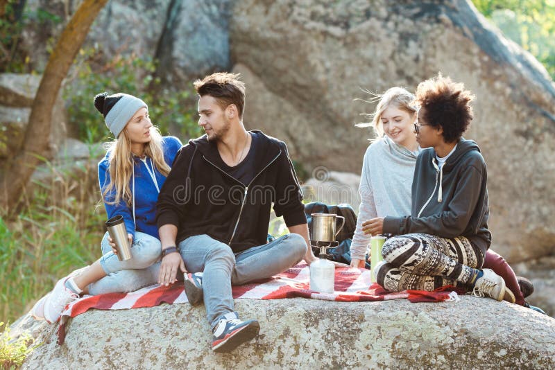 Young Friends Sitting on Rock in Canyon, Smiling, Drinking Tea. Stock ...