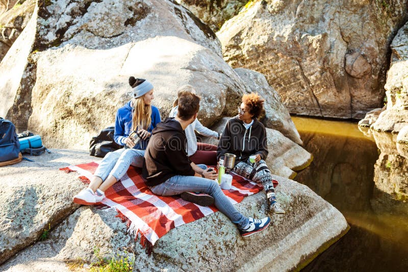 Young Friends Sitting on Rock in Canyon, Smiling, Drinking Tea. Stock ...